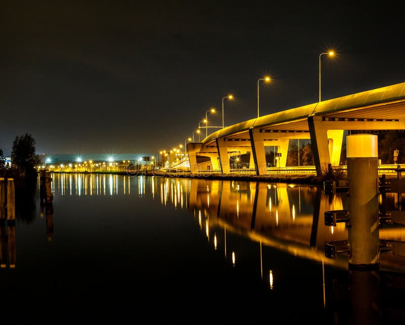 Massive Bridge with Lights Next To the Sea with City Skyline in the ...