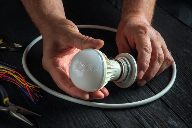 Master Electrician Turns on Light Bulb. Close-up of Worker Hands on a ...