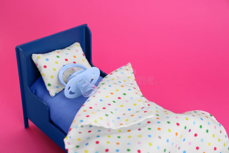 Maternity Leave Concept. Toy Bed with Baby Pacifier on Pink Background ...