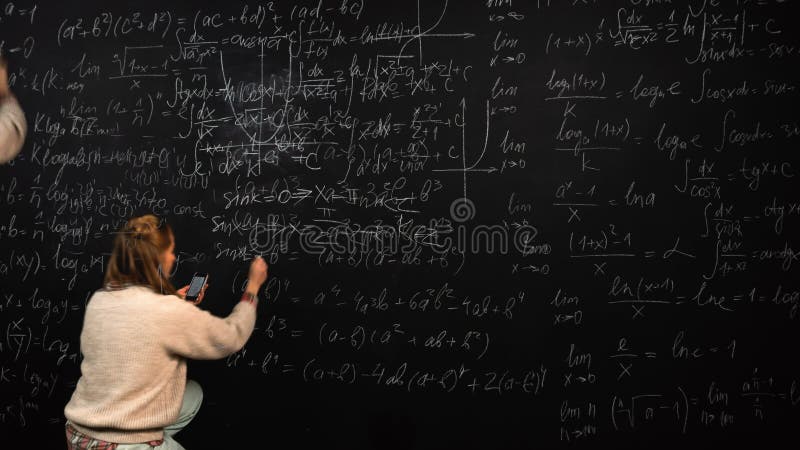 A Mathematics Professor is Writing Algebra Formulas on a Blackboard in ...