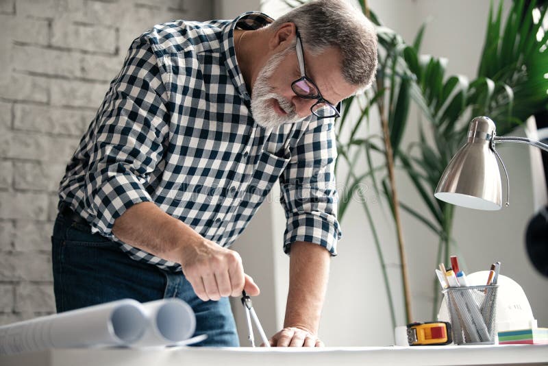 Mature Architect Working on Construction Blueprint in Modern Office ...