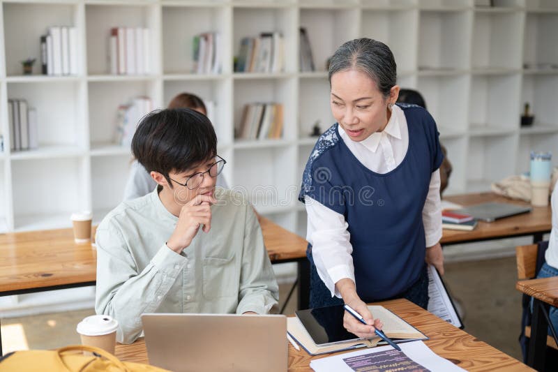 A Mature Asian Female Teacher Helping and Explaining Difficult Math ...
