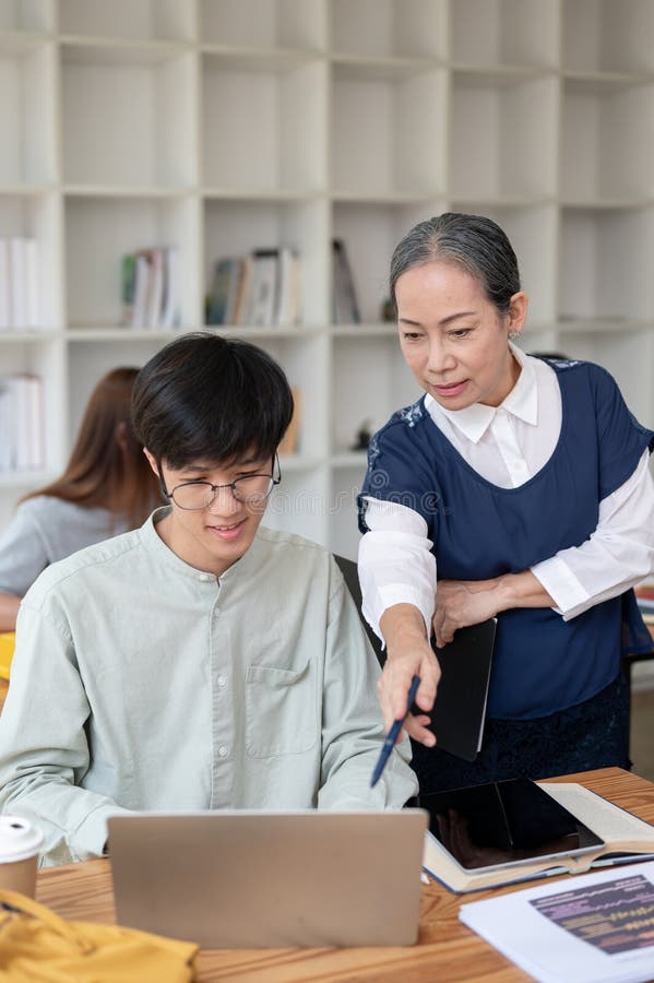 A Mature Asian Female Teacher Helping and Explaining Difficult Math ...