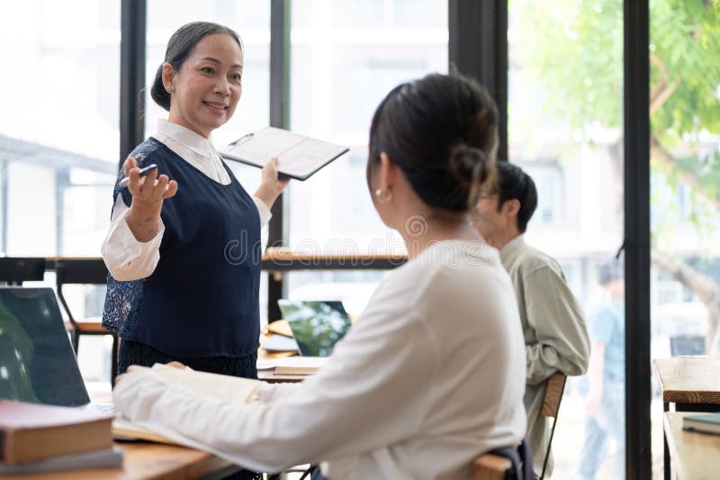 A Mature Asian Female Teacher Helping and Explaining Difficult Math ...