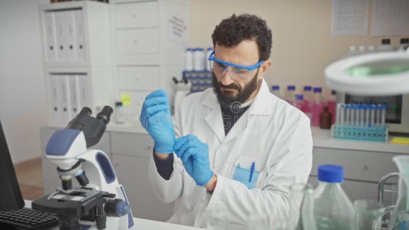 A Mature Bearded Man in a Lab Coat Adjusts Blue Gloves in a Laboratory ...