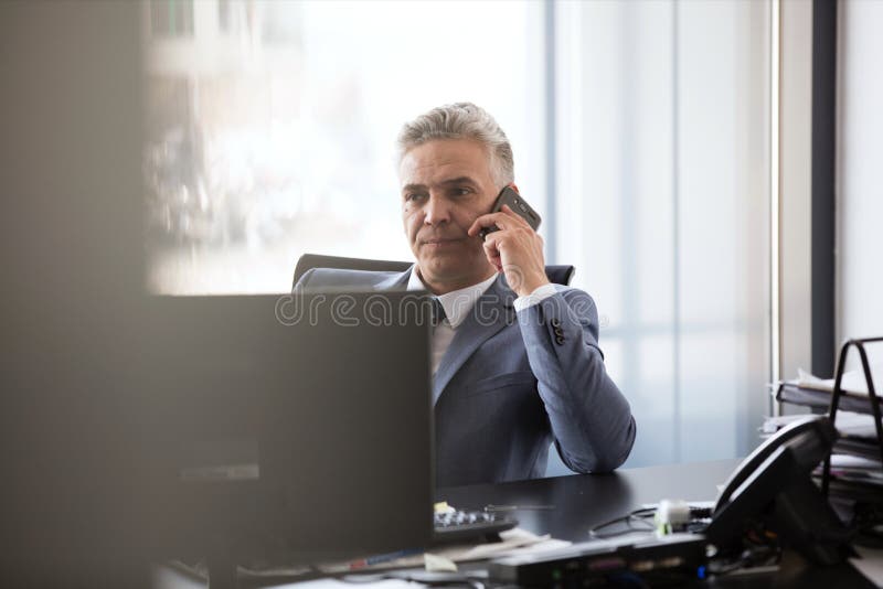 Mature Businessman Using Mobile Phone at Desk in Office Stock Image ...
