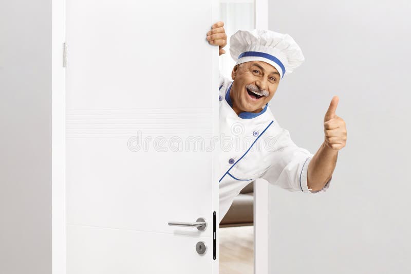 Mature Chef in a Uniform Gesturing Thumbs Up Behind a Door Stock Photo ...