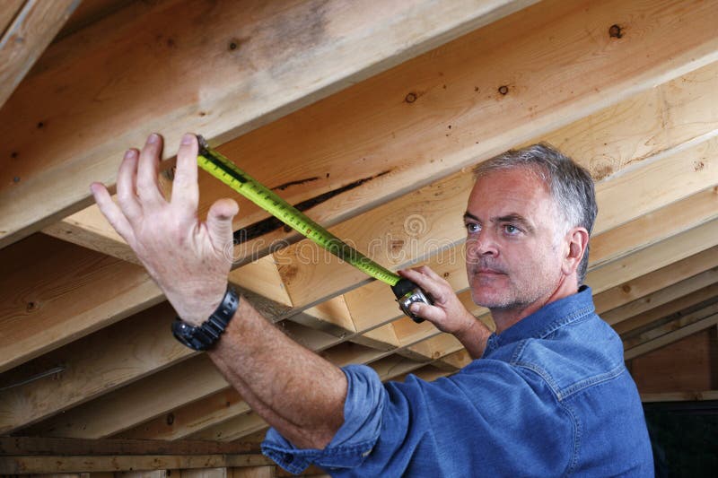 Mature Construction Worker Measuring Distance between Rafter Beams ...
