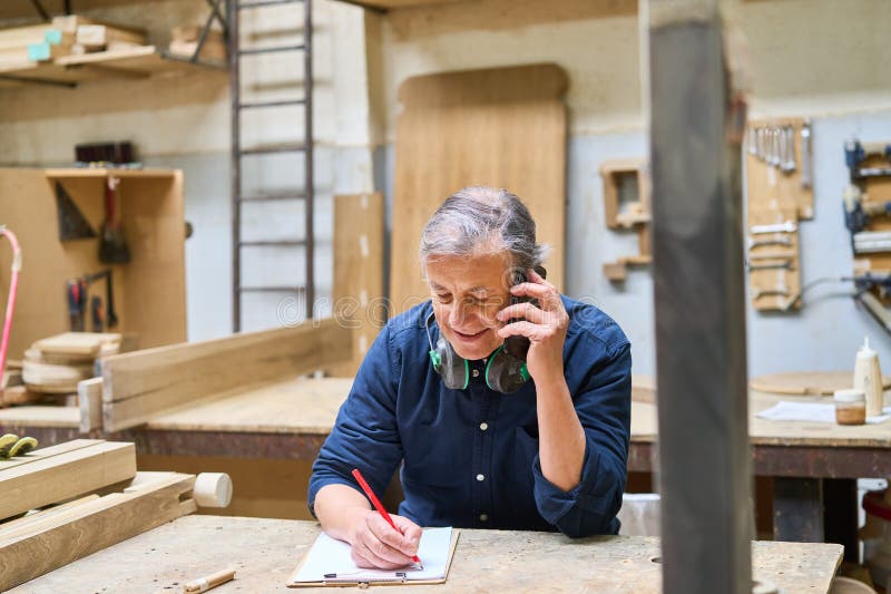 Mature Craftsman in a Lumberyard Taking Notes on a Phone Call Stock ...