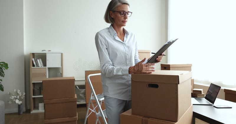 Mature Ecommerce Storage Owner Making Record List Over Paper Containers ...