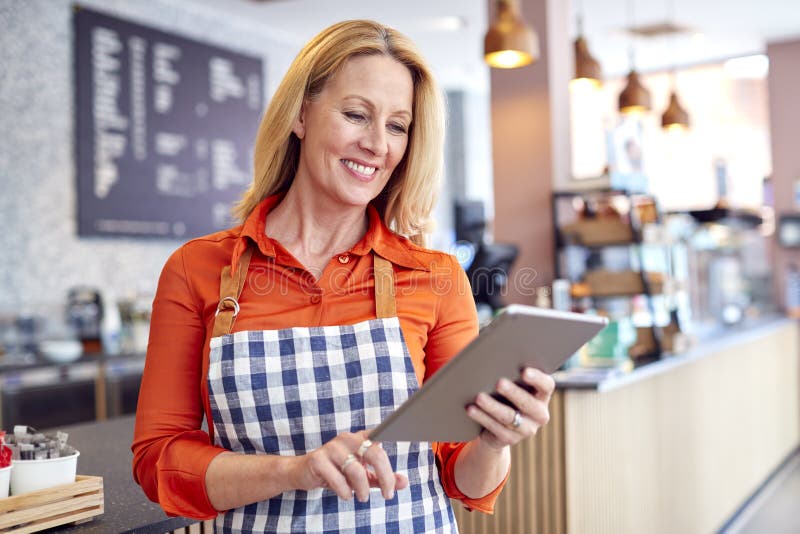 Mature Female Owner of Coffee Shop or Restaurant Using Digital Tablet ...
