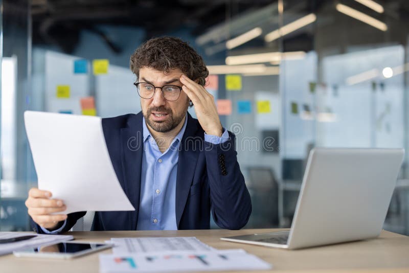 Concerned Mature Financier Reviewing Important Documents at Office Desk ...