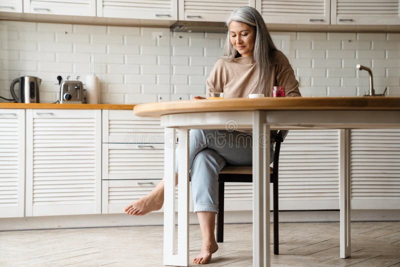 Mature Grey Woman Having Breakfast while Sitting in Kitchen Stock Image ...