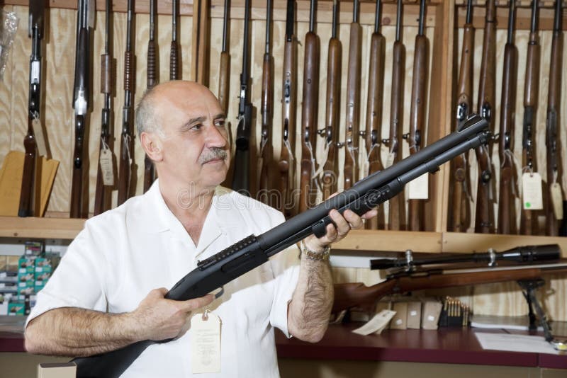 Mature Gun Store Owner Looking at Weapon in Shop Stock Image - Image of ...