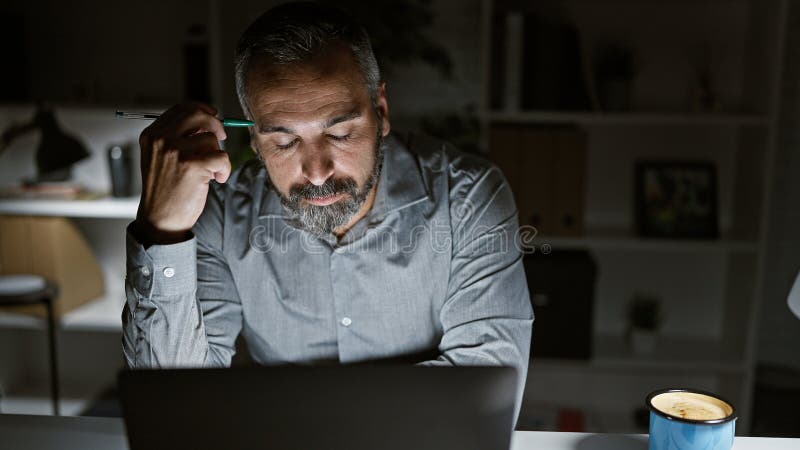 Mature Hispanic Man with Beard and Grey Hair Focused on Work at Night ...