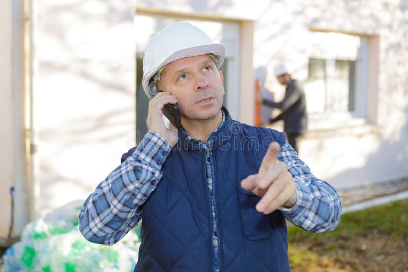 Mature Male Architect Pointing at Construction while Using Phone Stock ...
