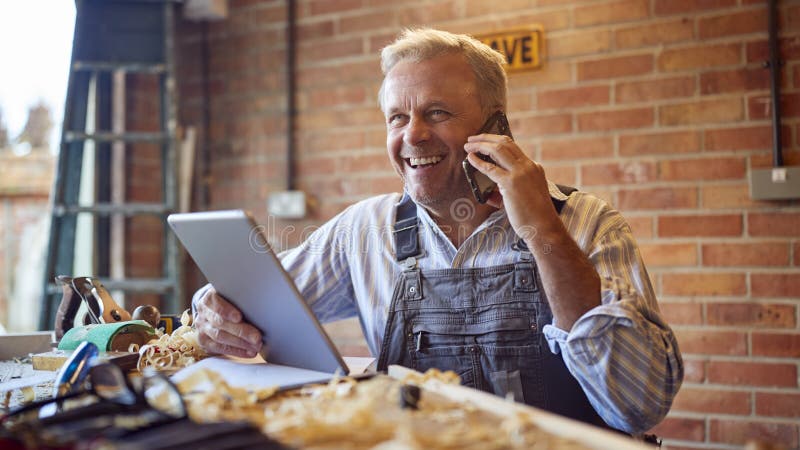 Mature Male Carpenter in Garage Workshop with Digital Tablet Talking on ...