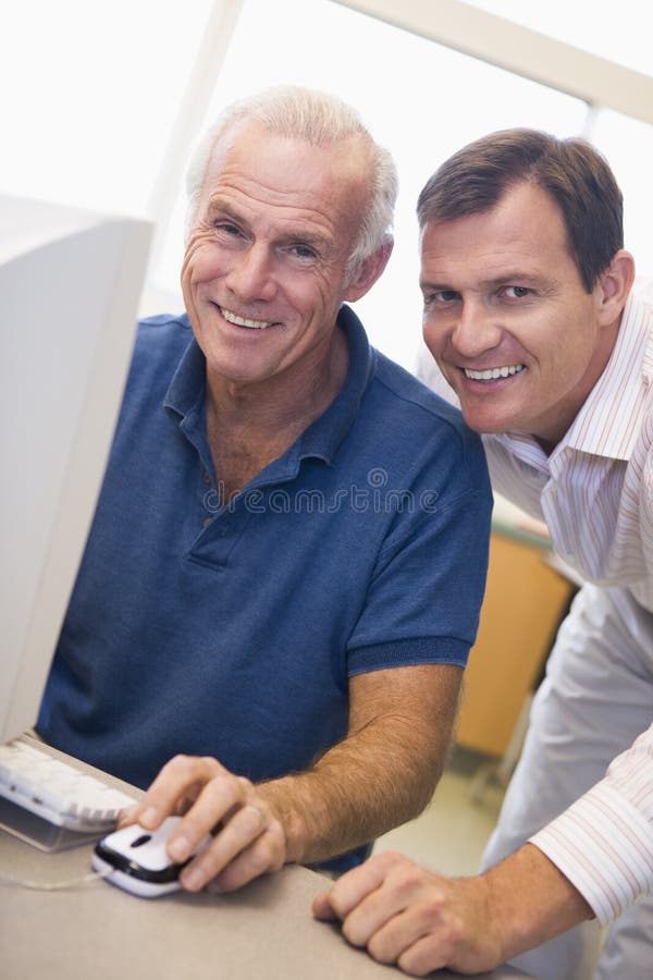 Volunteers Teaching a Senior How To Use a Computer Stock Photo - Image ...