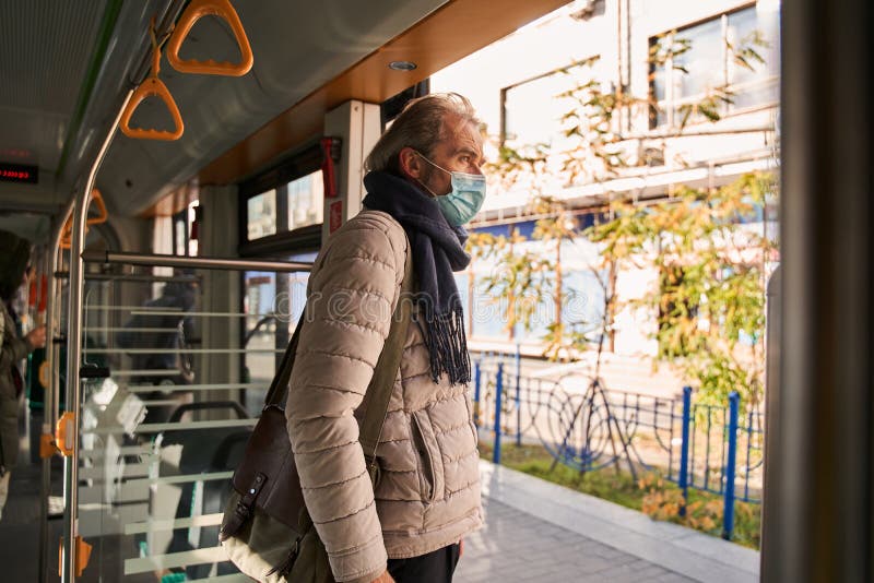 Mature Man Adjusting Face Mask While Riding Train Or Bus Stock Image