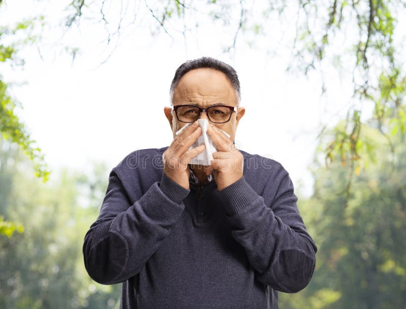 Mature Man Blowing Nose with a Paper Tissue in a Park with Trees Stock ...