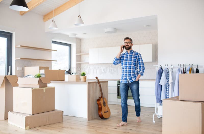 Mature Man with Boxes Moving in New House, Using Smartphone. Stock ...