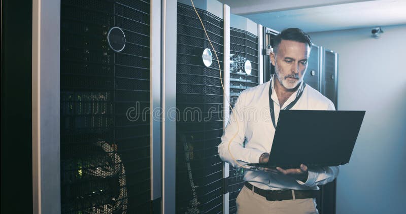 Man in Data Center with Laptop, Typing and Network Maintenance with ...