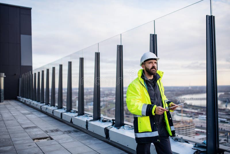 Man Engineer Walking on Construction Site, Holding Tablet. Stock Image ... Man Engineer Walking on Construction Site, Holding Tablet. Stock Image ...