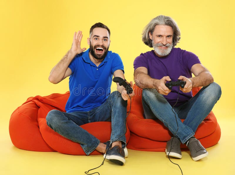 Mature Man and Guy Playing Video Games on Color Background Stock Photo ...