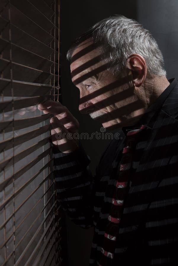 Mature Man Looking Out of a Window with Blinds Casting Shadows Stock ...