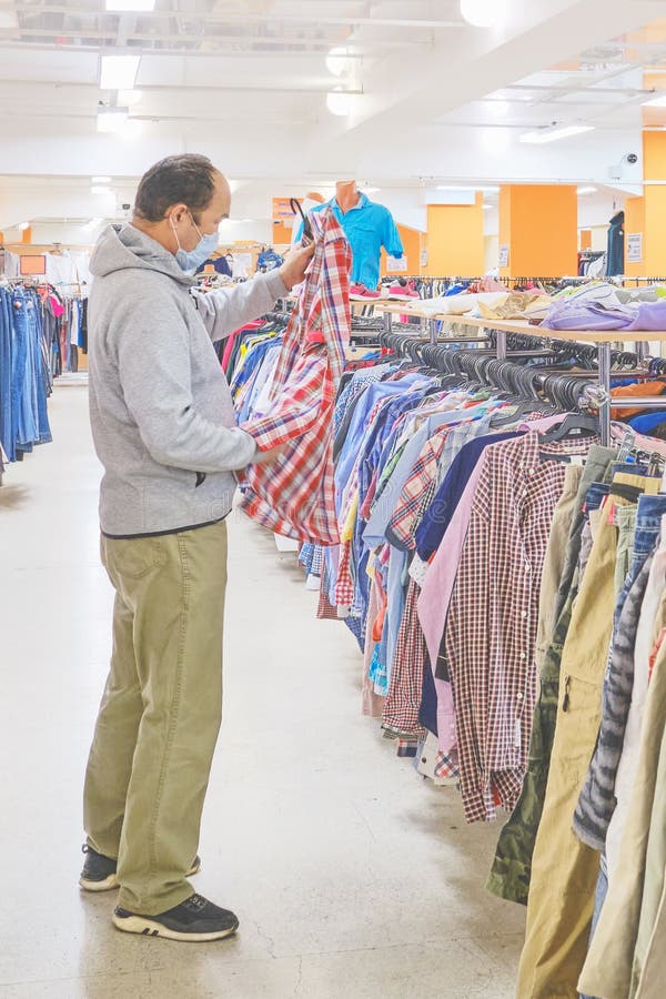 Mature Man in Mask Choosing Clothes at Second Hand Store Stock Photo ...