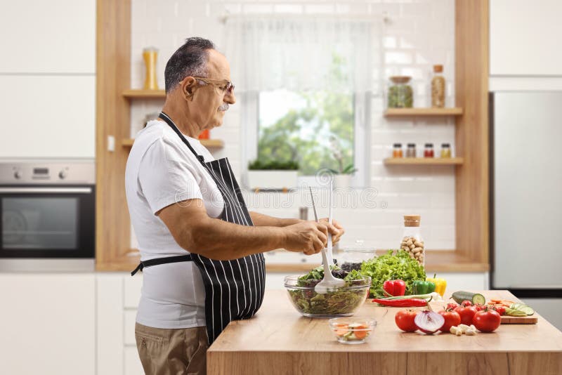 Mature Man Mixing a Salad on a Kitchen Counter Stock Photo - Image of ...
