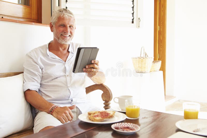 Mature Man Sitting at Breakfast Table Using Digital Tablet Stock Photo ...