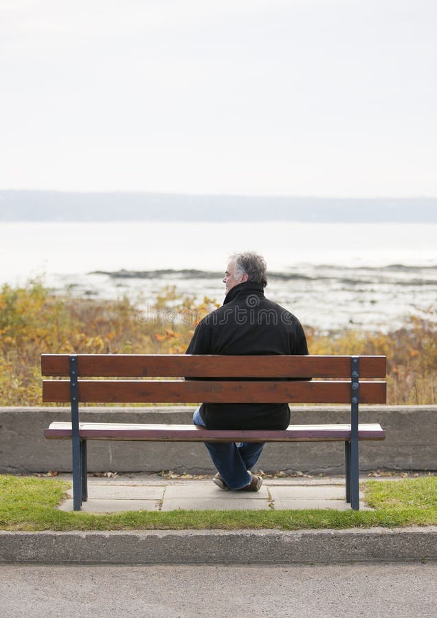 Mature Man Sitting on Park Bench Overlooking River in Autumn. Stock ...