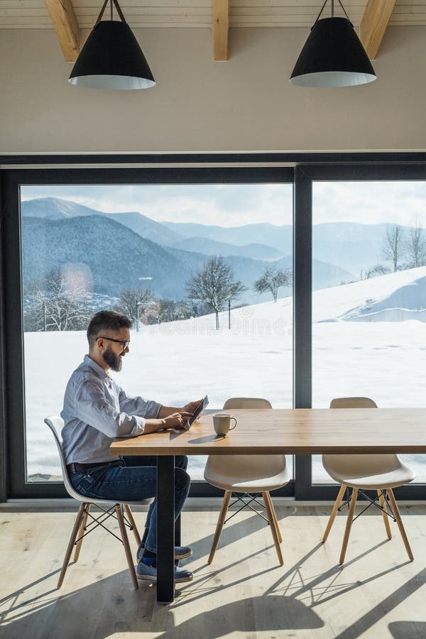 A Mature Man Sitting at the Table in New Home, Using Tablet. Stock ...