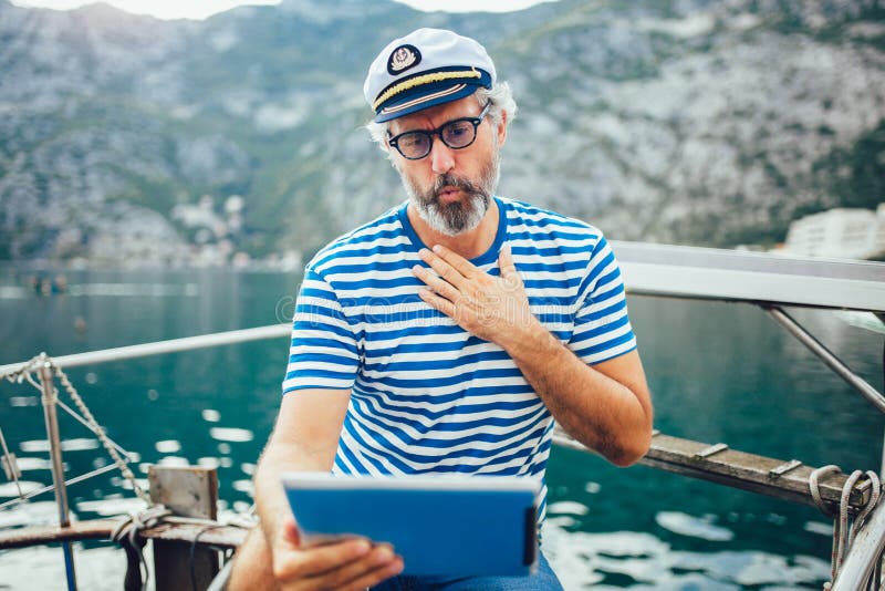 Man Standing on the Deck of His Boat and Using Digital Tablet on a ...
