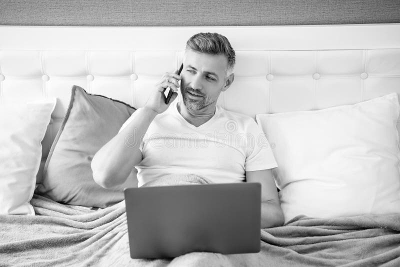 Mature Man Talk on Phone and Working on Laptop in Bed Stock Photo ...