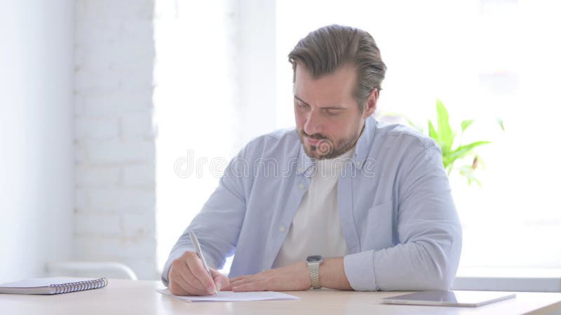 Young Man Writing on Paper in Office Stock Photo - Image of office ...