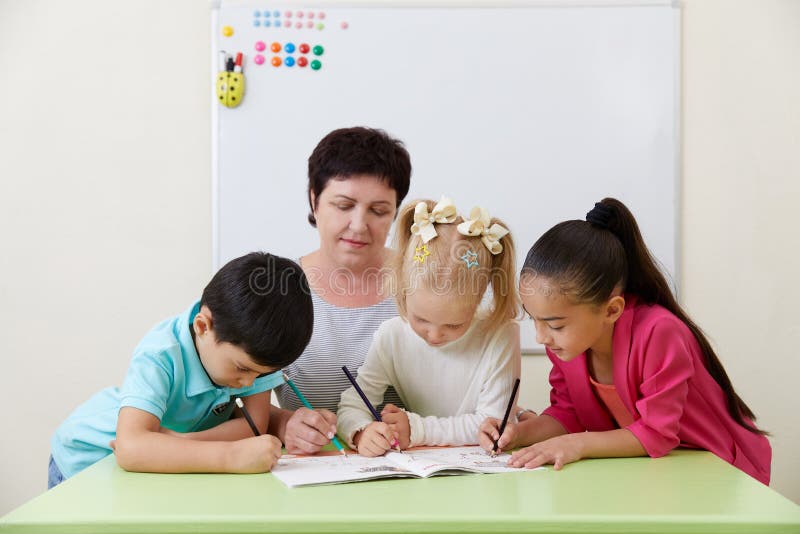 Mature Preschool Teacher and Children in a Classroom during Class Stock ...