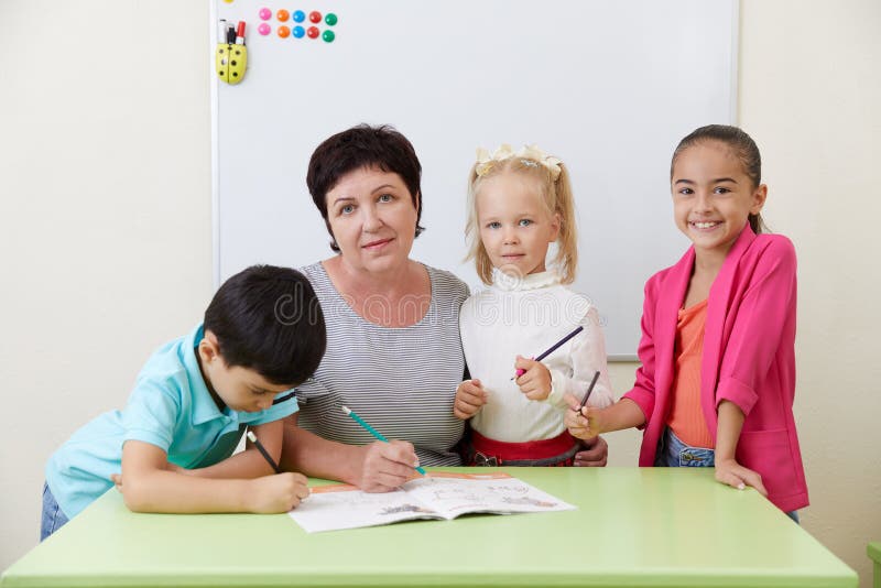 Mature Preschool Teacher and Children in a Classroom during Class Stock ...