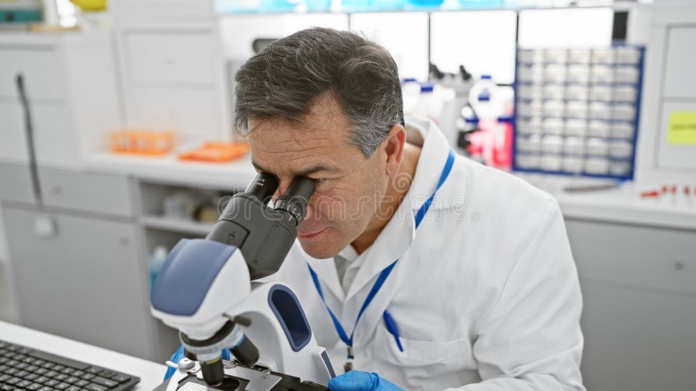 Mature Scientist Man in Lab Examining Samples with Microscope in a ...