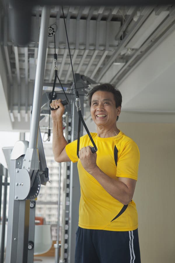 Mature Smiling and Man Working Out at the Gym on a Machine Stock Photo ...