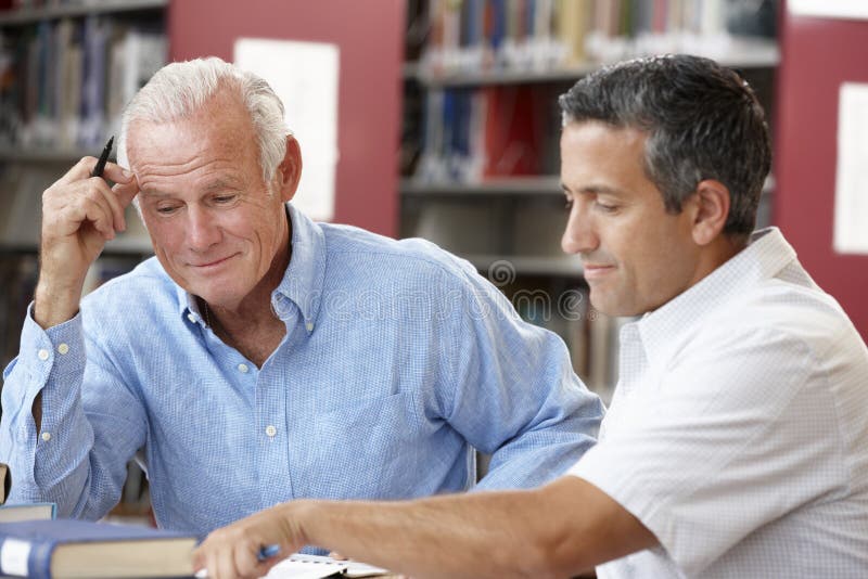Tutor Assisting Mature Student in Library Stock Image - Image of mature ...