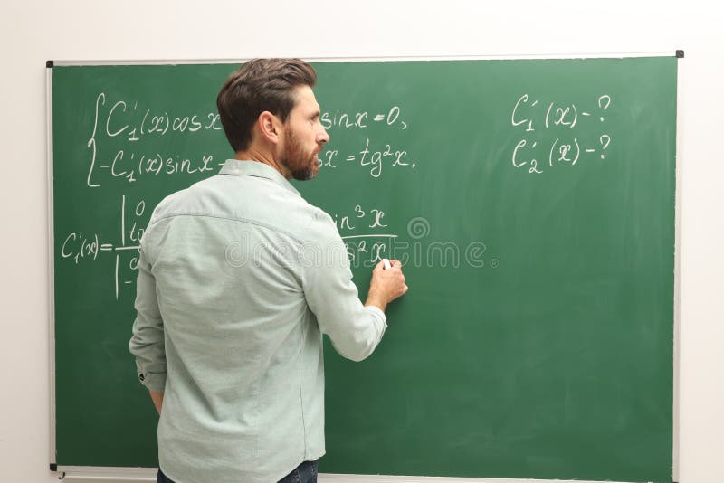 Mature Teacher Explaining Mathematics at Chalkboard in Classroom Stock ...