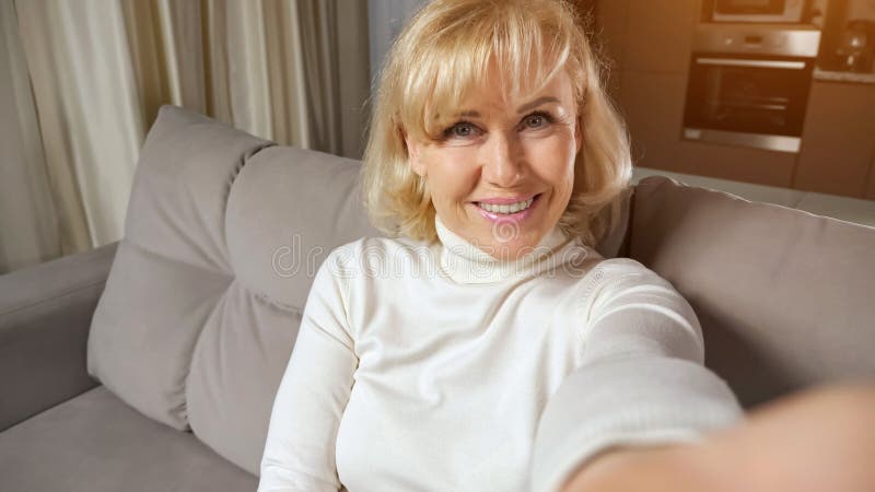 Mature Woman With Blonde Hair Takes Selfies And Smiles Stock Image