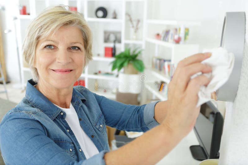 Mature woman dusting home stock photo. Image of cloth - 262492350