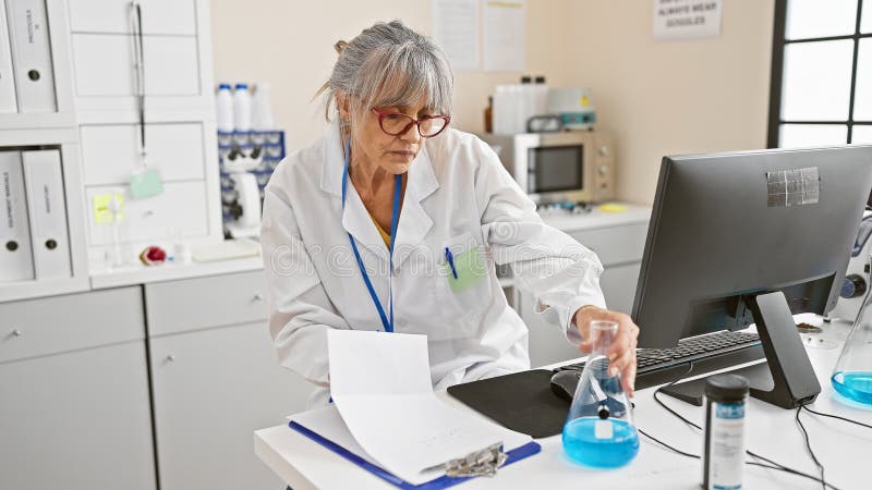 Mature Woman Scientist in Lab Analyzes Data on Computer with Flask ...