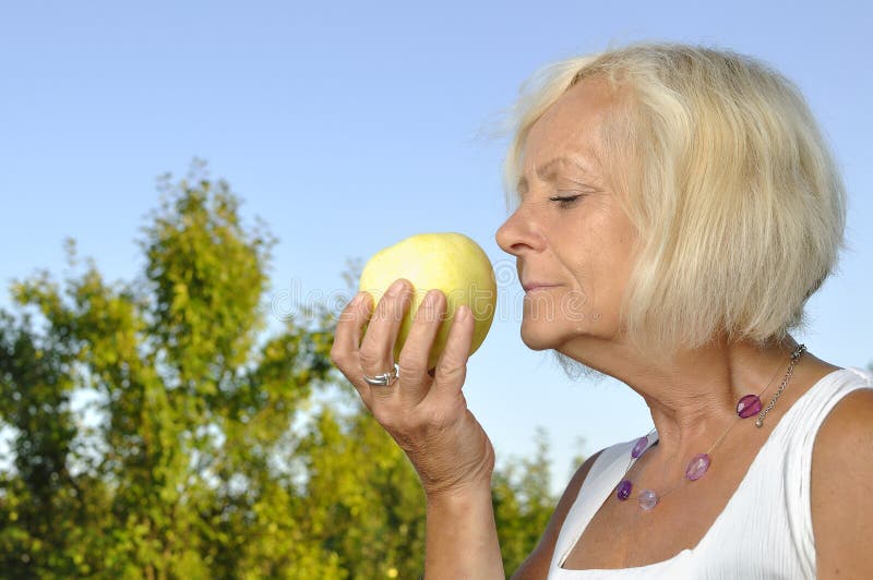 Mature Woman Smelling Apple. Stock Image - Image of holds, outdoor ...