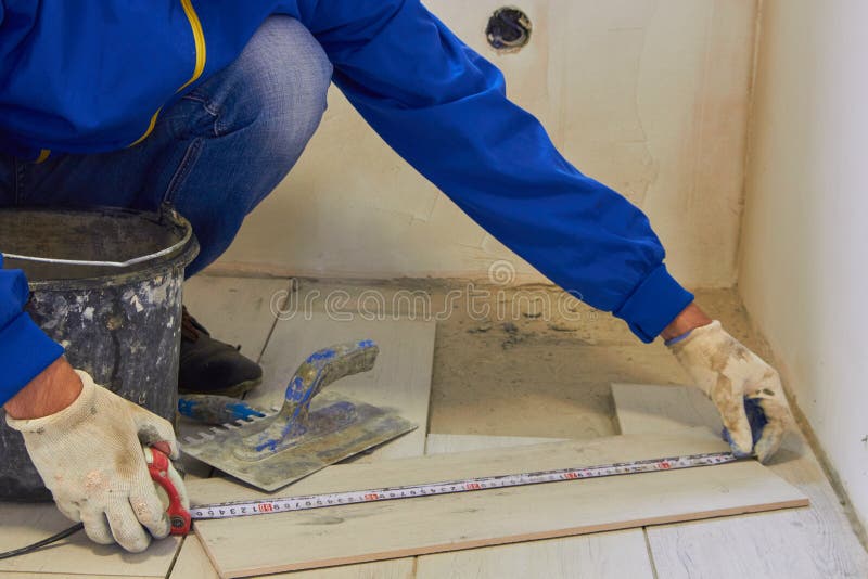 Measure the Tile with a Tape Measure,a Worker when Laying Tiles ...