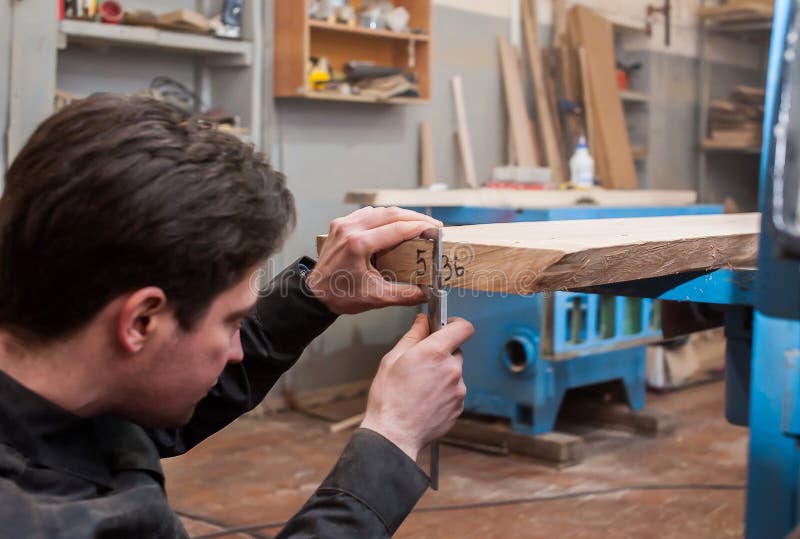 Measuring Board Thickness with a Caliper. Carpenter Working in ...