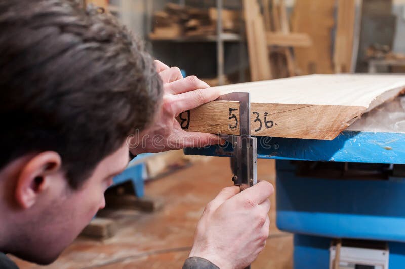 Measuring Board Thickness with a Caliper. Carpenter Working in ...